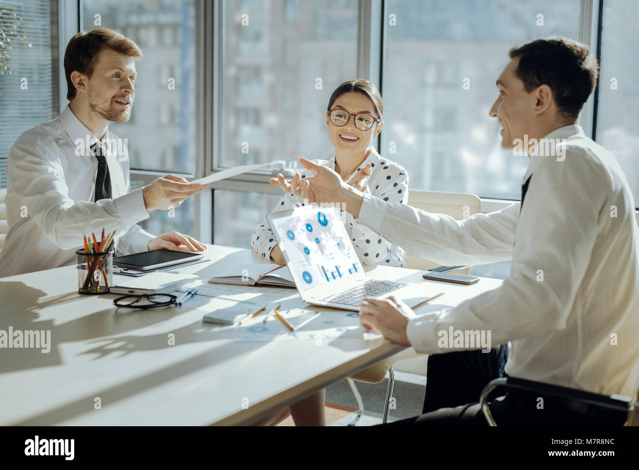 Young man distributing copies to his colleagues during meeting Stock ...
