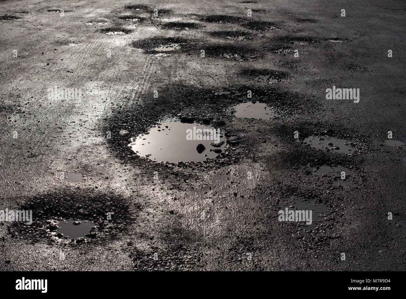potholes in the road with water looking like an alien planet landscape ...