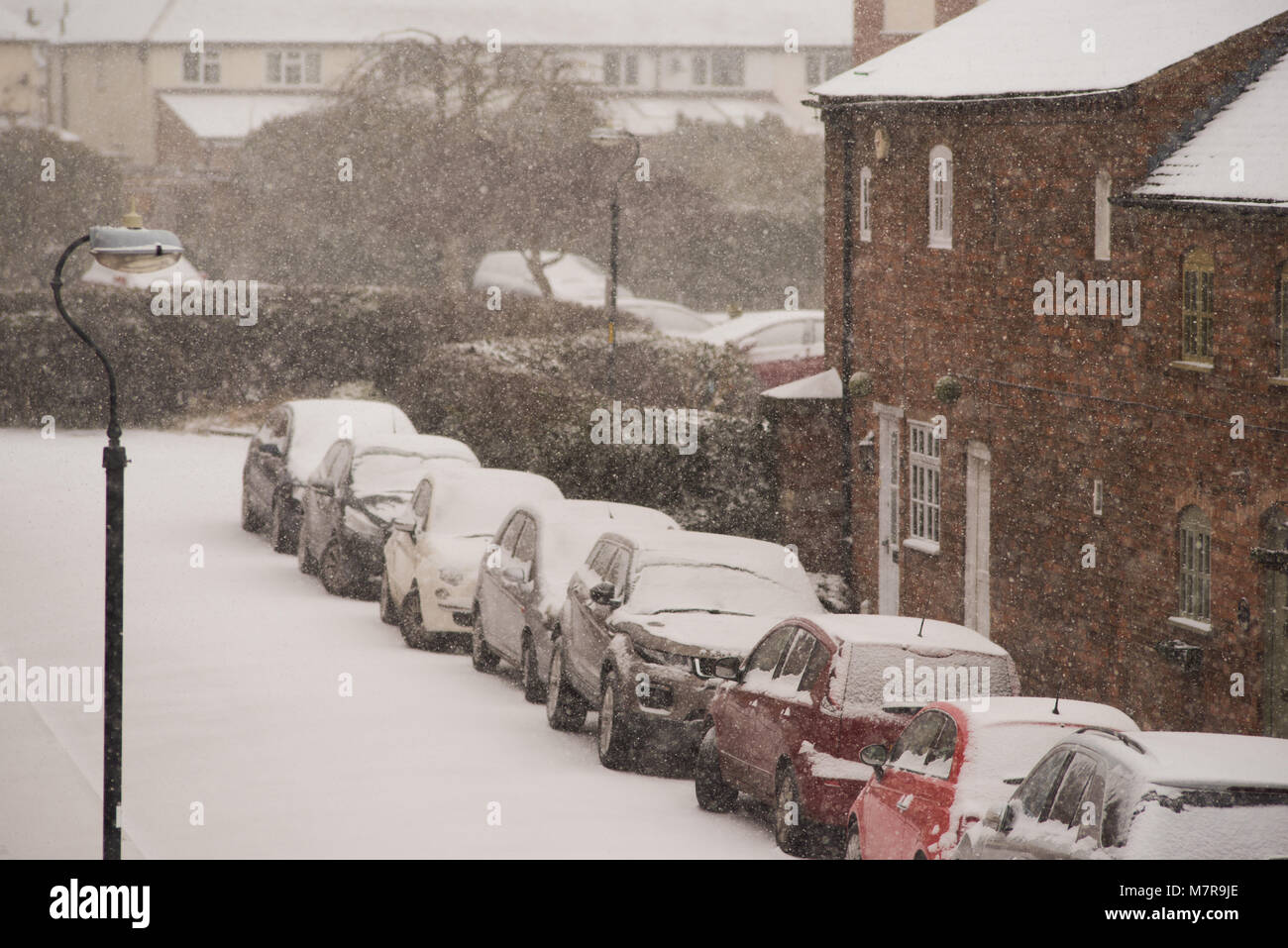 row of parked cars stuck in snow during blizzard in UK Stock Photo - Alamy