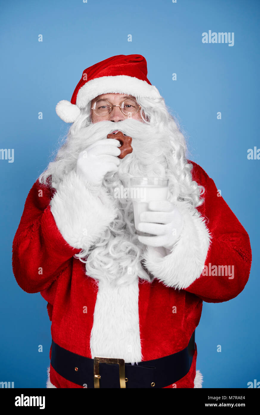 Hungry santa claus eating cookie at studio shot Stock Photo - Alamy