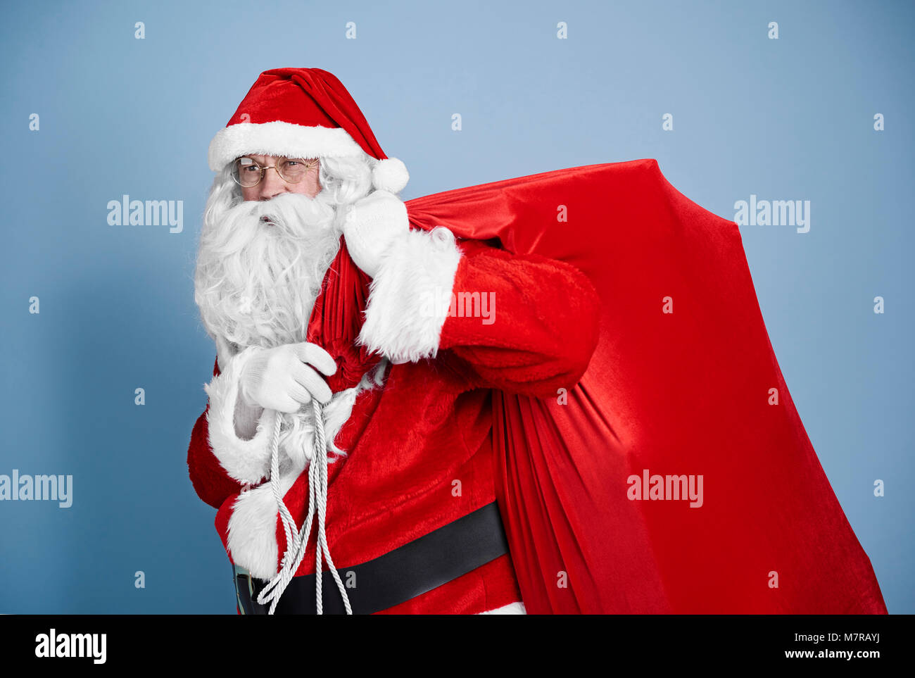 Tired santa claus carrying heavy sack Stock Photo - Alamy