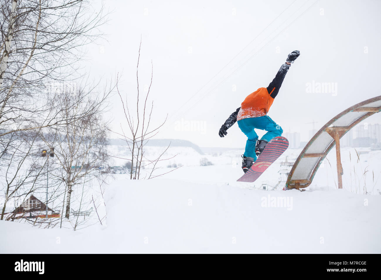 Photo from back of young athlete skating on snowboard with springboard ...