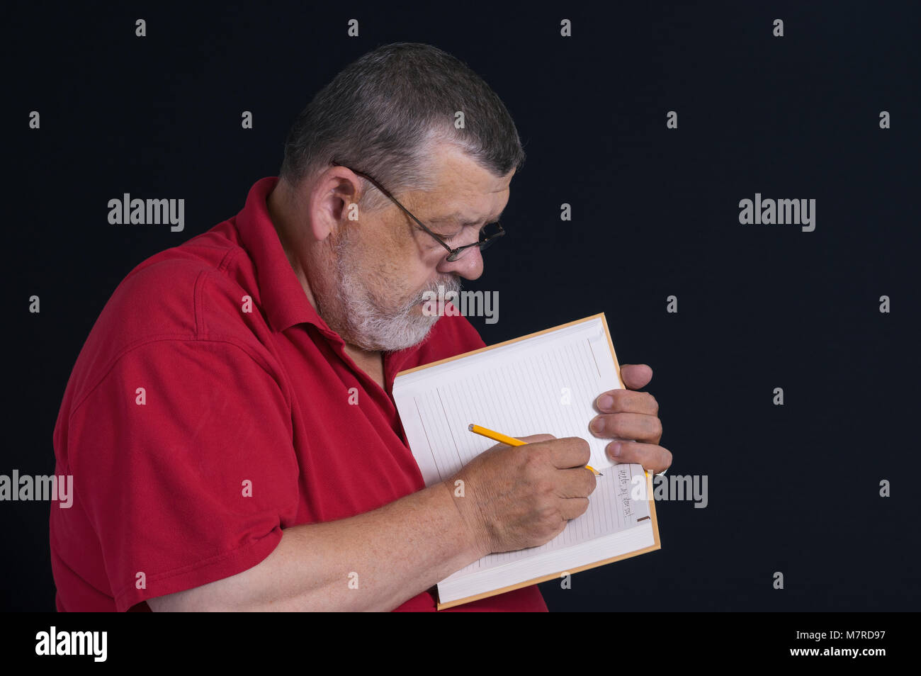 Nice low key portrait of a bearded senior writing a letter to his son ...