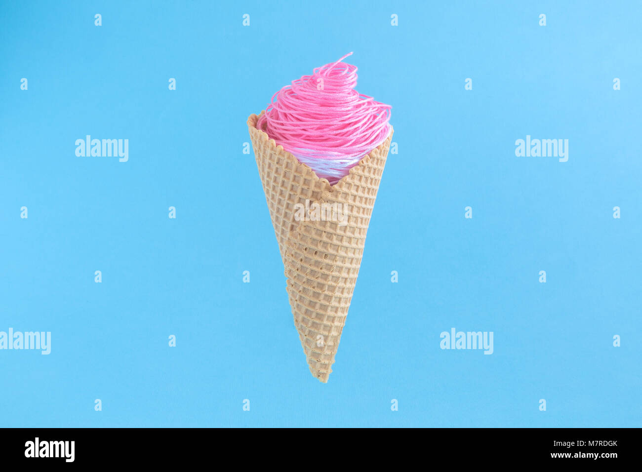 Ice cream made of colorful strings in cone on blue pastel background ...