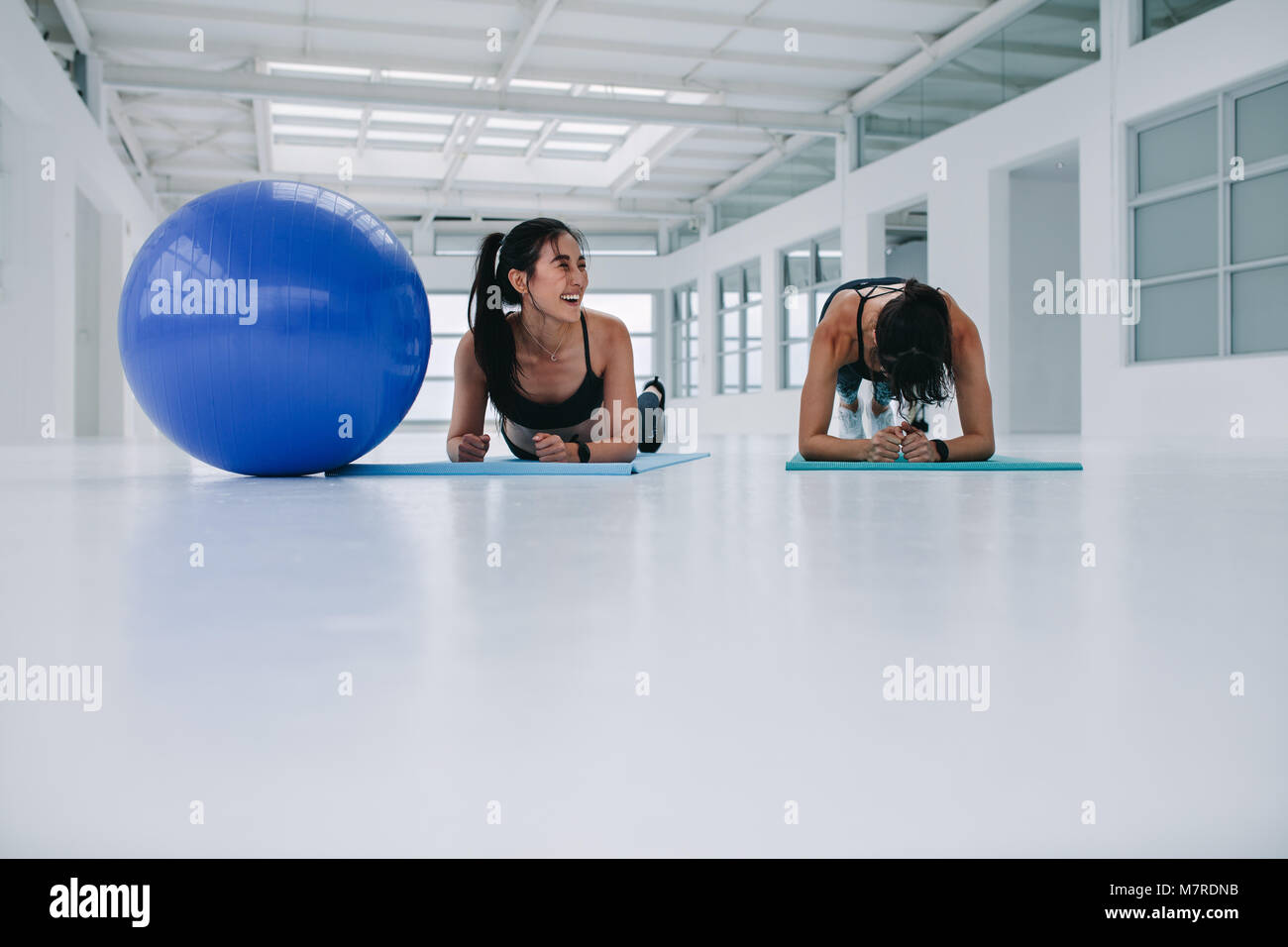 Two sporty girls working out together in gym. Females exercising and ...