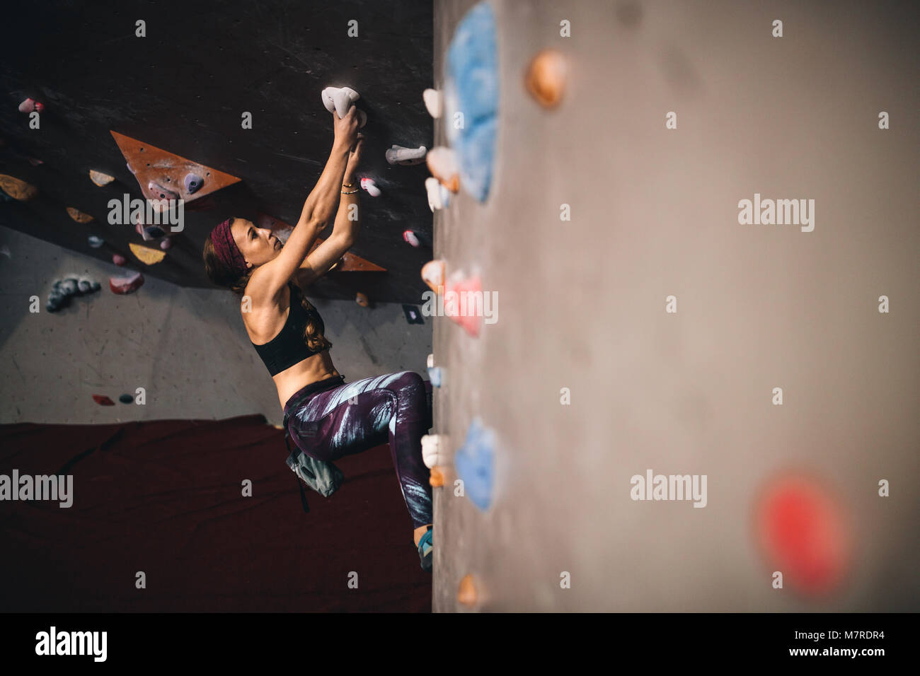 Athletic woman bouldering at an indoor climbing centre. Woman climber ...