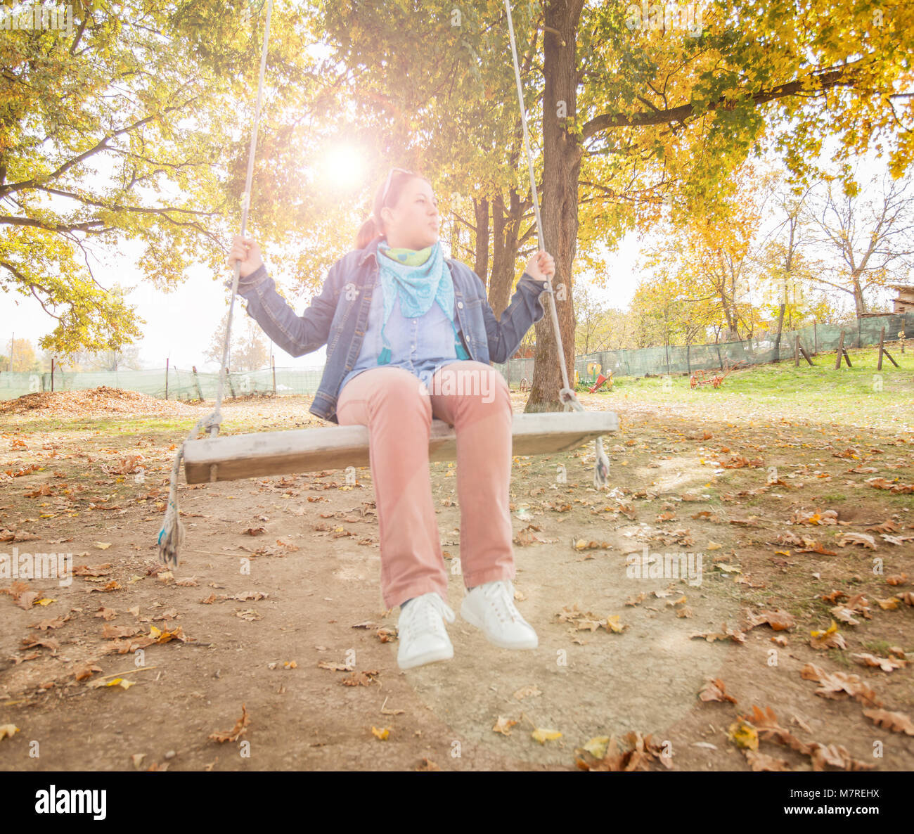 Happy young woman in casual clothes relax on swing with sunlight in ...
