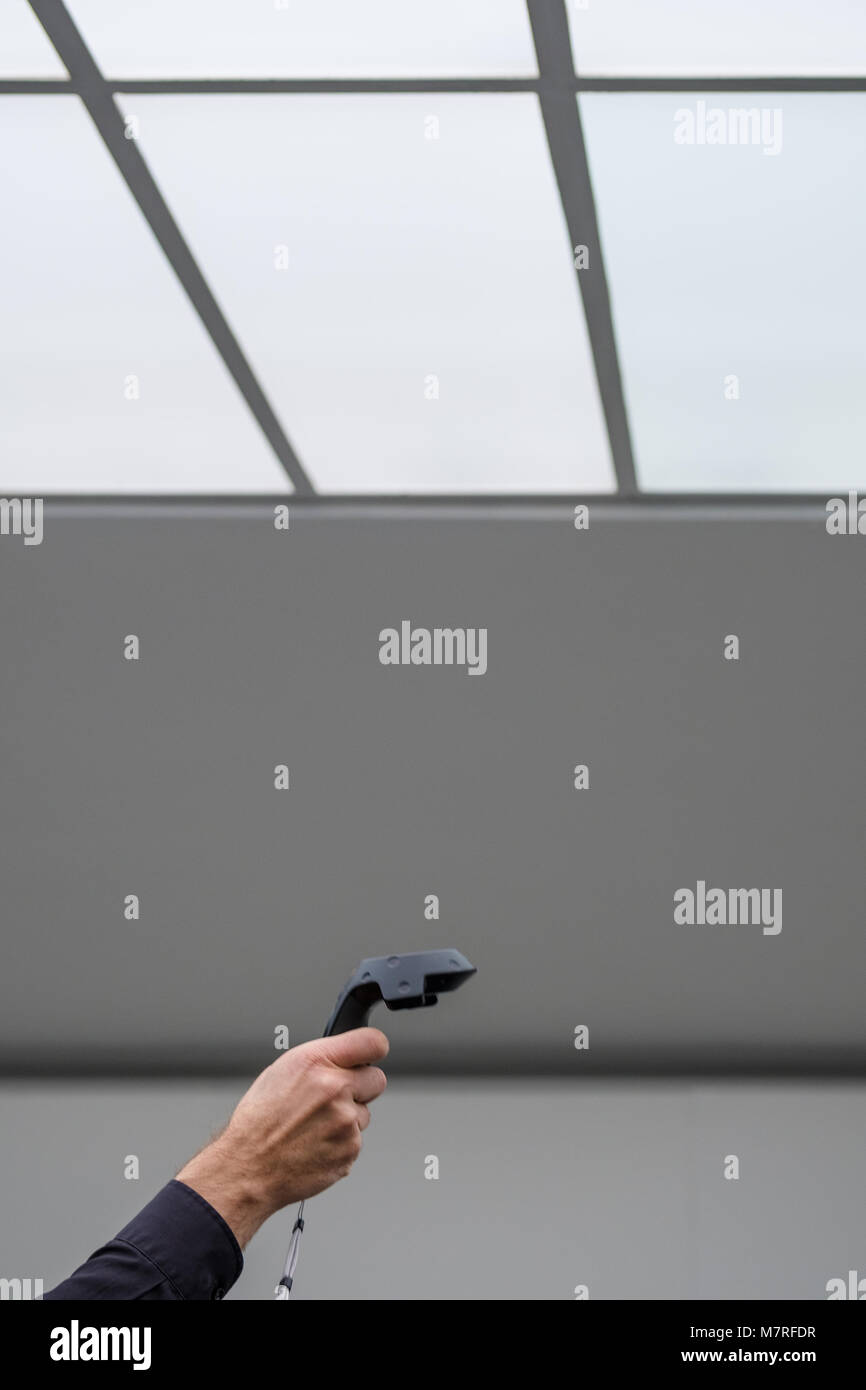 Male hand holds a virtual reality remote controller in a modern grey ...