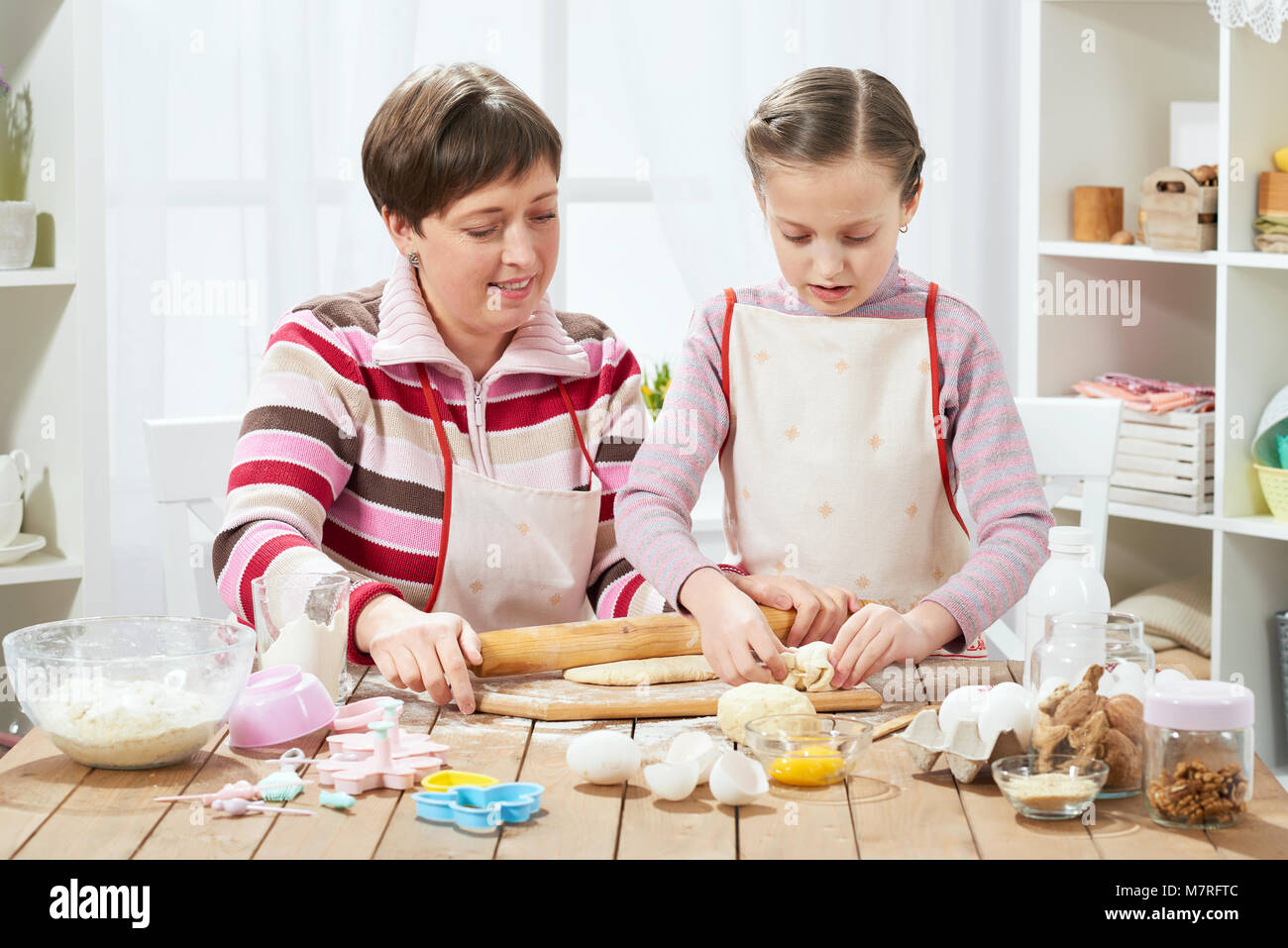 Mother and daughter cooking at home, making the dough for buns Stock ...