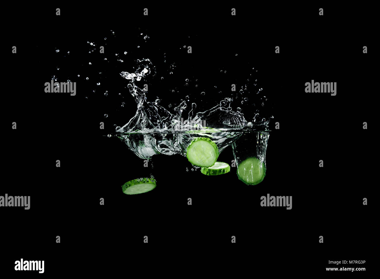 green cucumber slices in water with splash on black background Stock Photo - Alamy