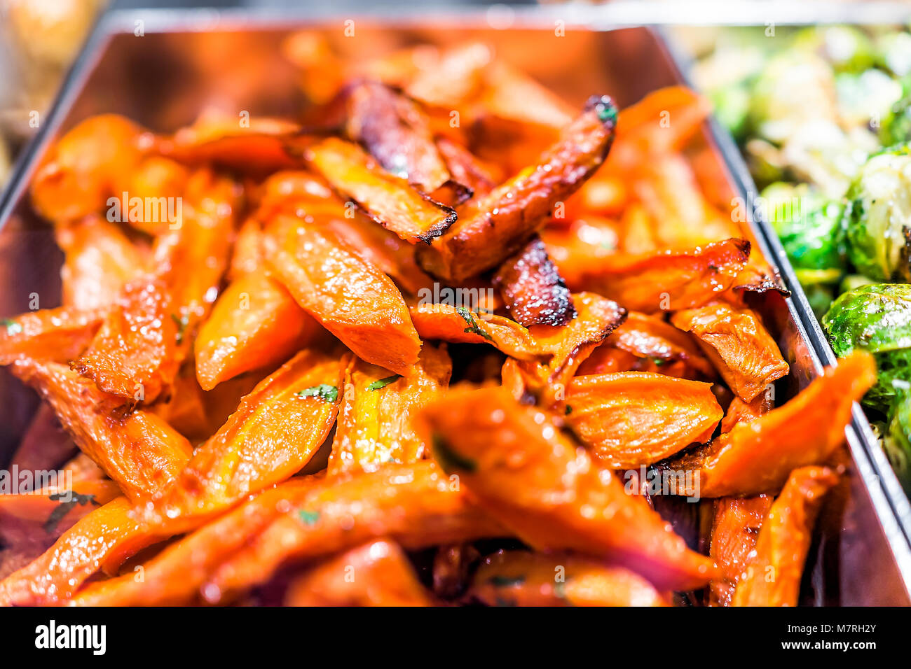 Macro closeup of oily greasy roasted shiny sweet potato slices in tray ...