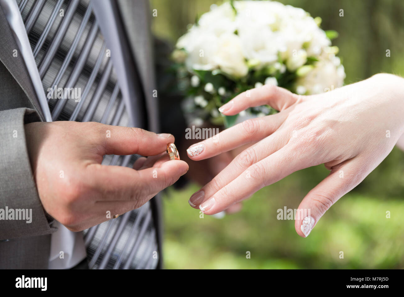A groom putting on ring on bride's finger Stock Photo - Alamy