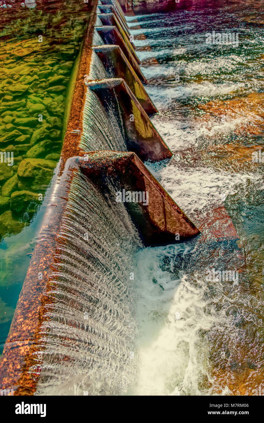 an artificial waterfall of water flows from the concrete dam of the ...