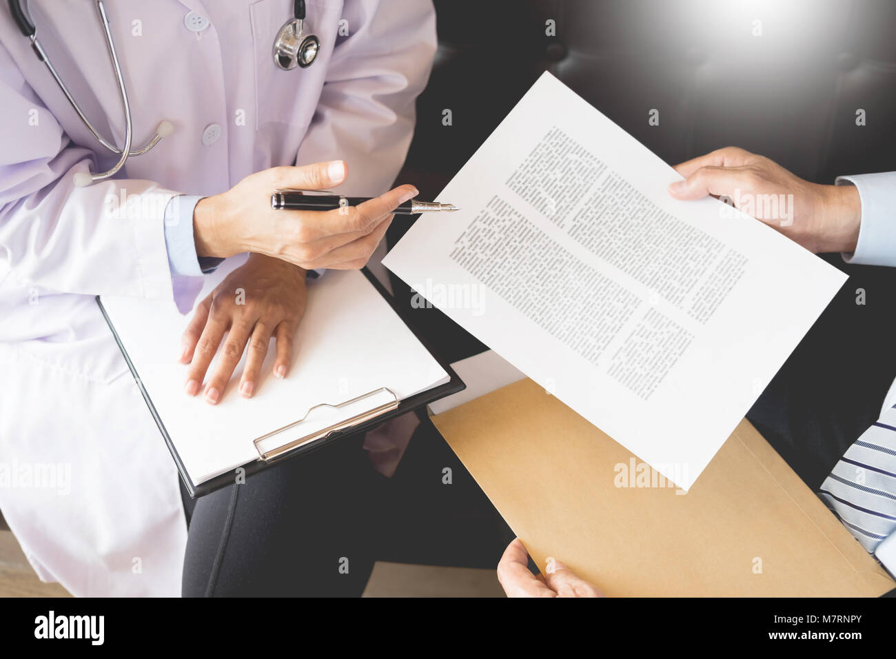Doctor informing patient's of diagnosis medical record from paper in ...