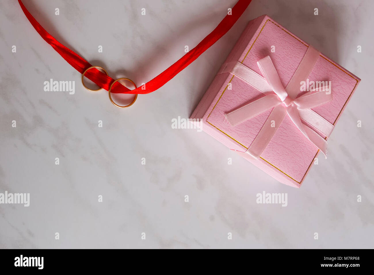 Wedding rings tied with red ribbon.Pink gift box Stock Photo - Alamy
