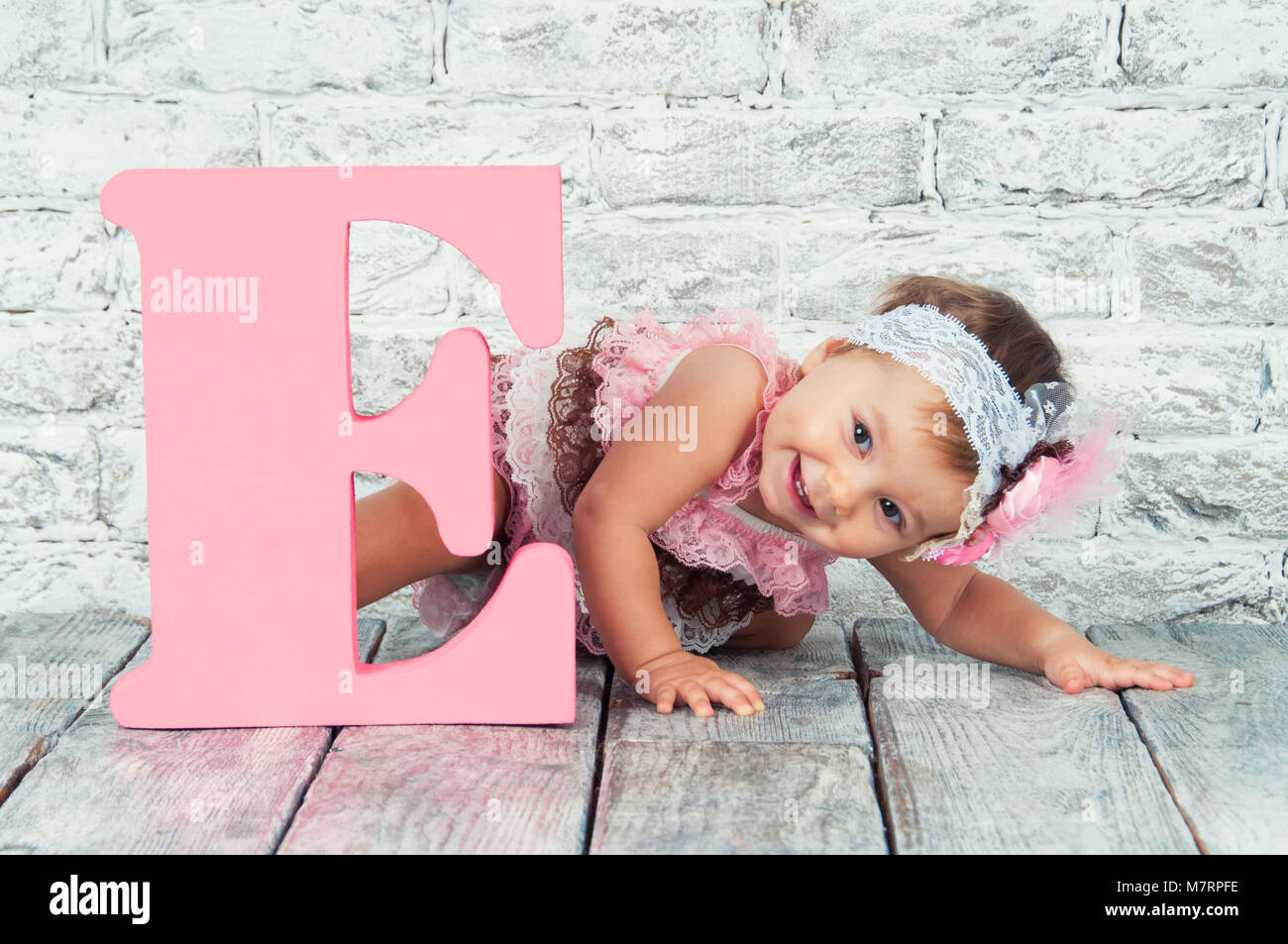 Beautiful and cute girl in pink dress with the letter E. Emotional girl ...