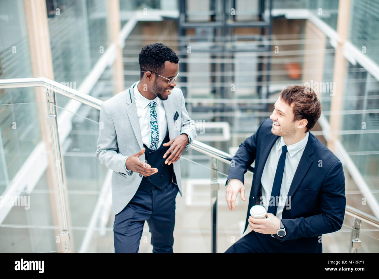 two multinational young businessmen interacting at meeting in office ...