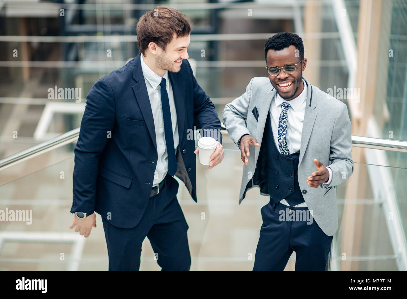 two multinational young businessmen interacting at meeting in office ...