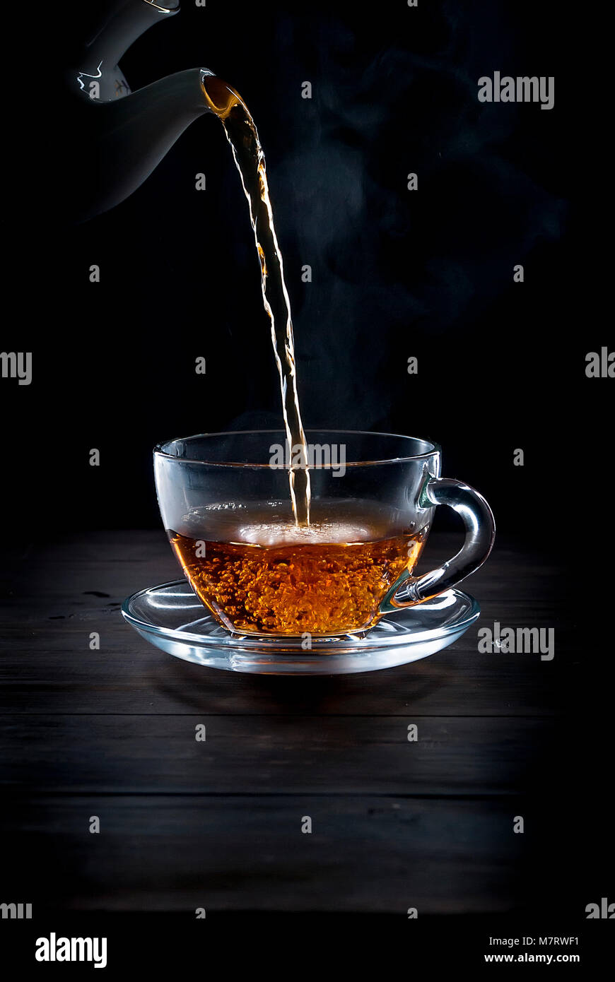 Pouring tea in glass cup on black background, liquid movement in a cup ...