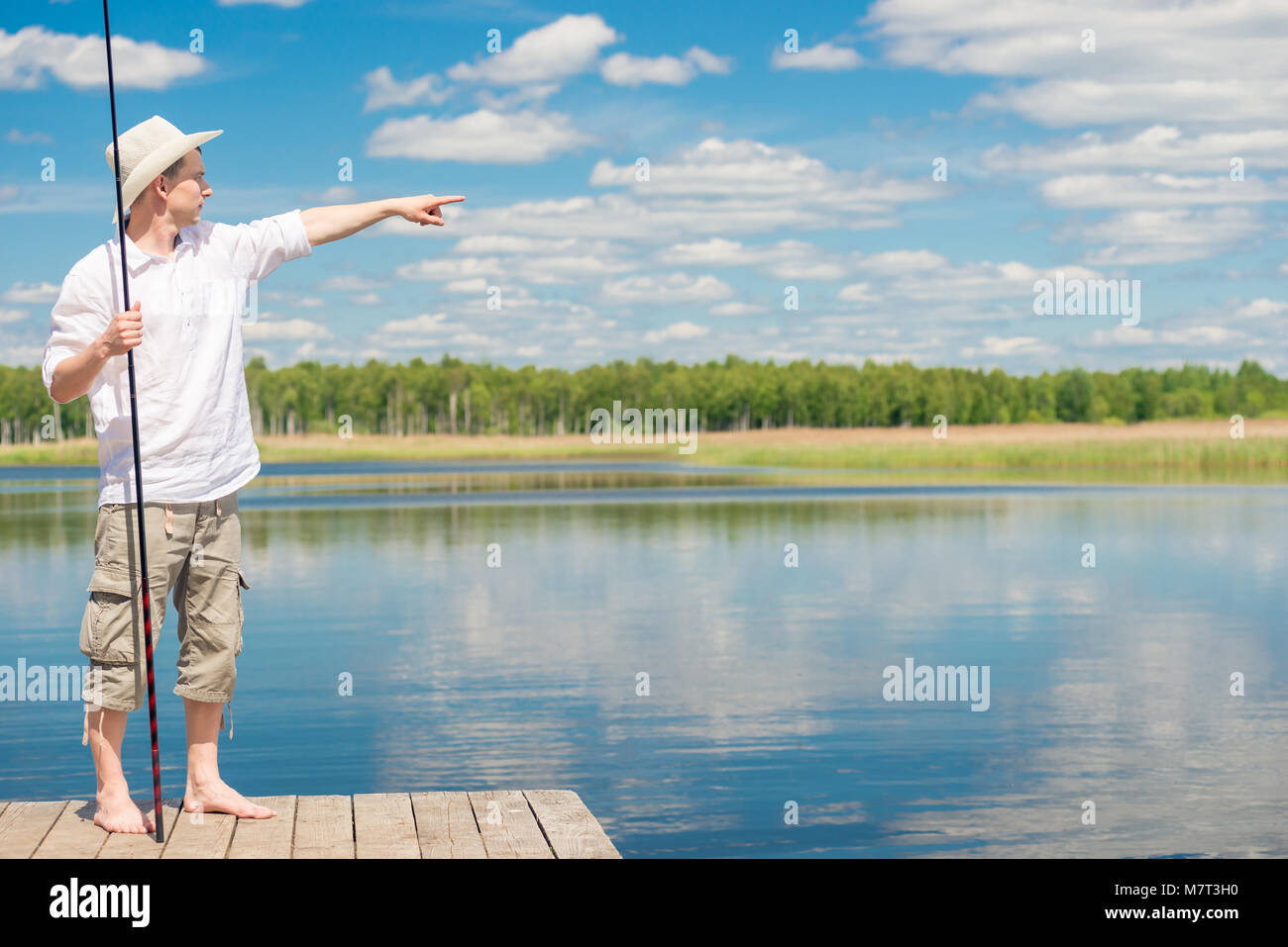 portrait of a fisherman on a pier pointing his hand into the distance ...