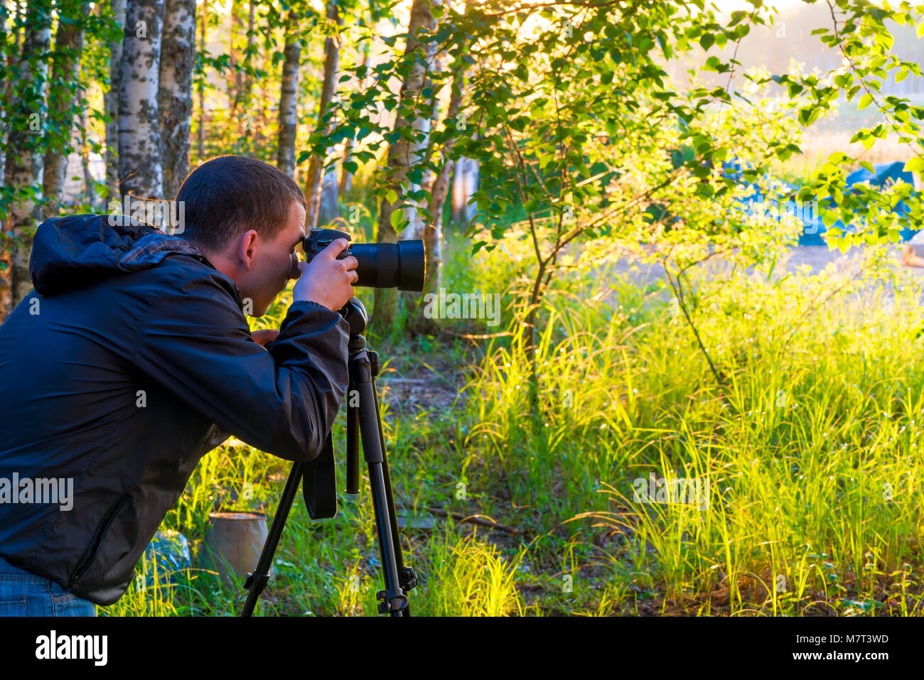 A man with a camera on a tripod takes pictures of nature Stock Photo ...