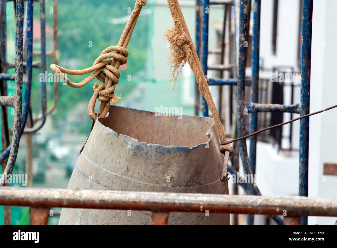 The barrel with building material hangs on the pulley at scaffold ...