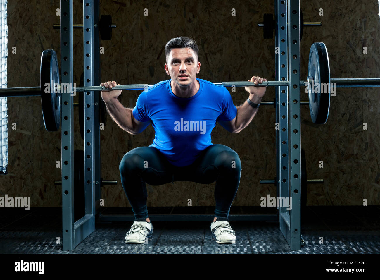 horizontal portrait of an athlete with a barbell makes an effort in the ...