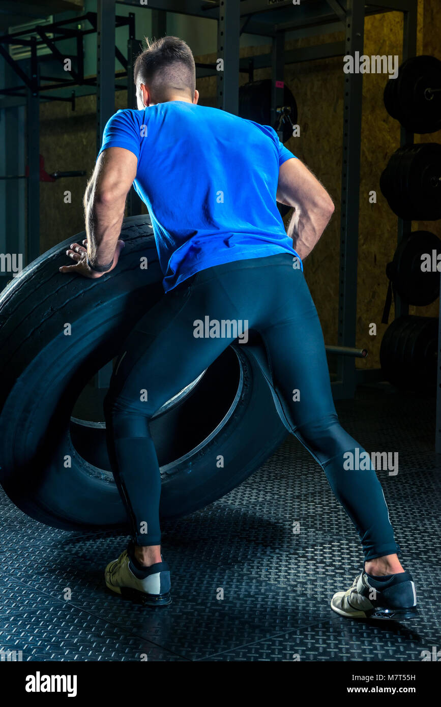 bodybuilder exercises in the gym with a heavy wheel, the view from the ...