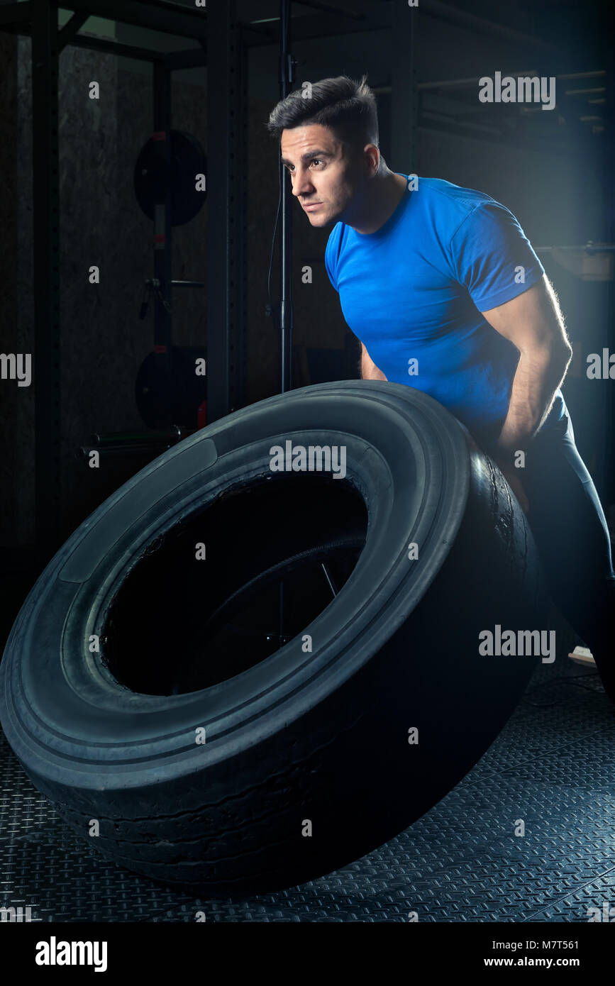 vertical portrait of a focused athlete posing with a heavy wheel in the ...
