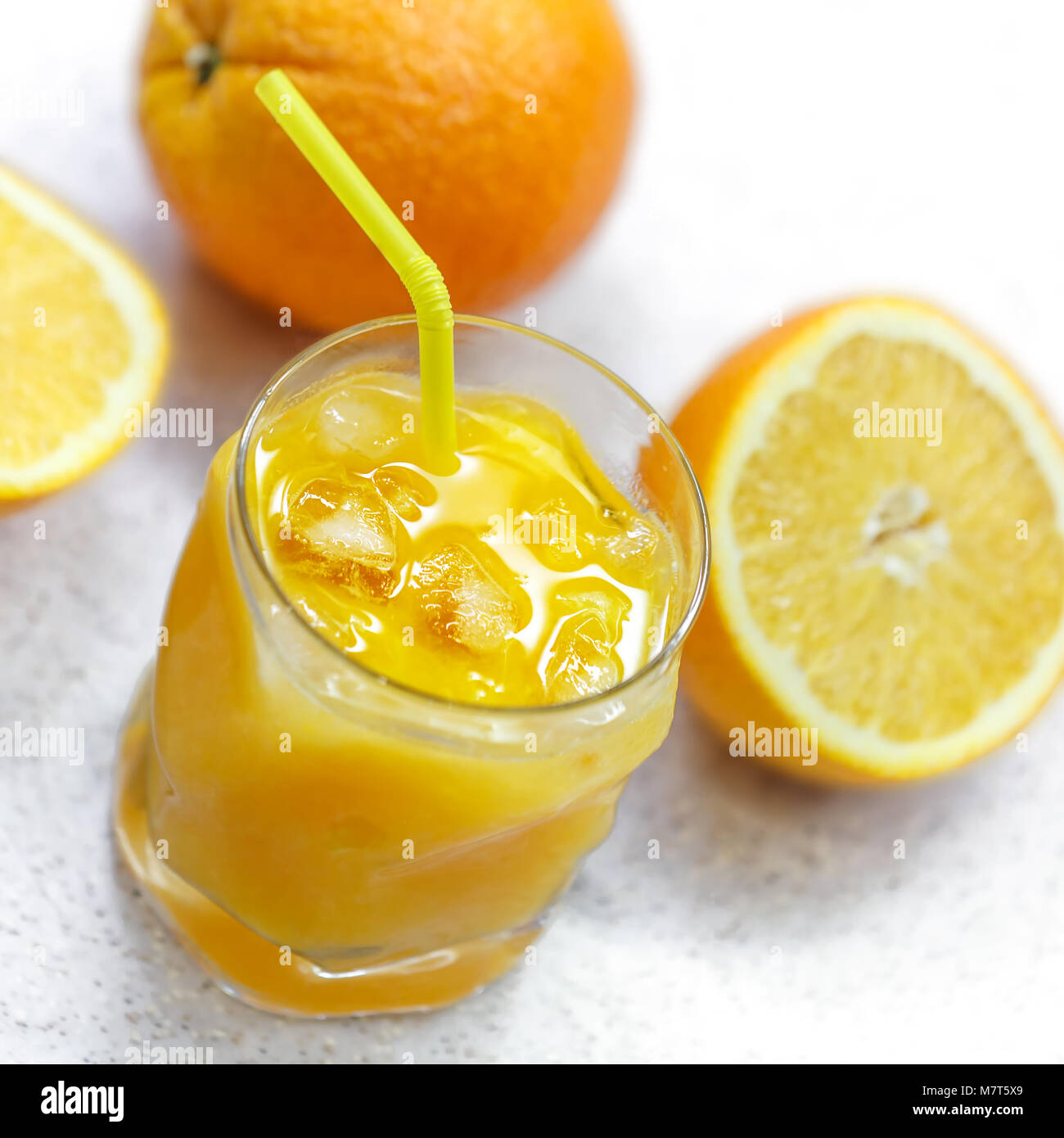 Glass of freshly squeezed orange juice with ice on a light gray ...