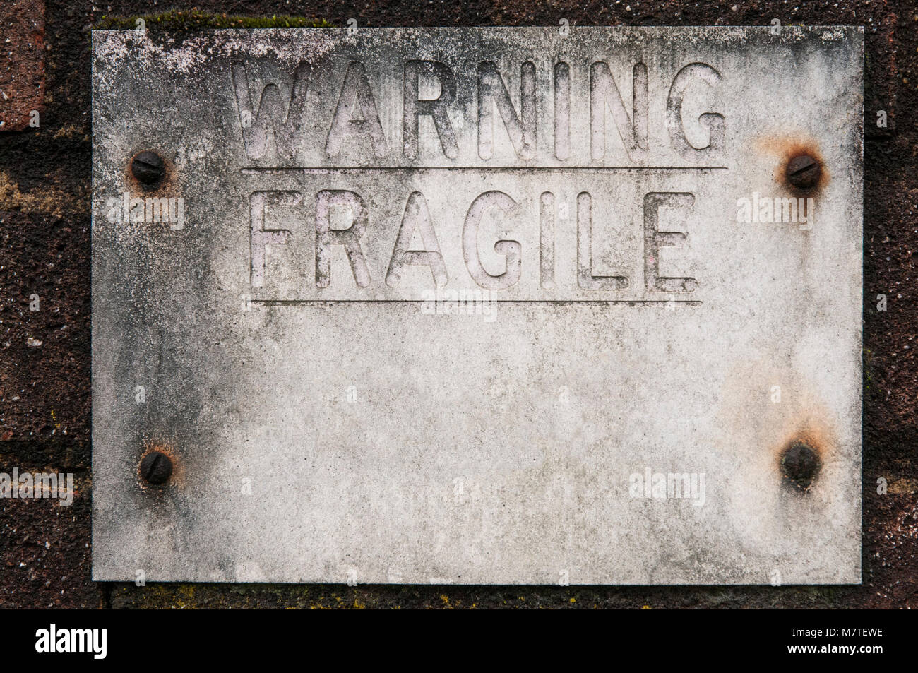 Weathered sign on brick wall saying WARNING FRAGILE Retouched for ...