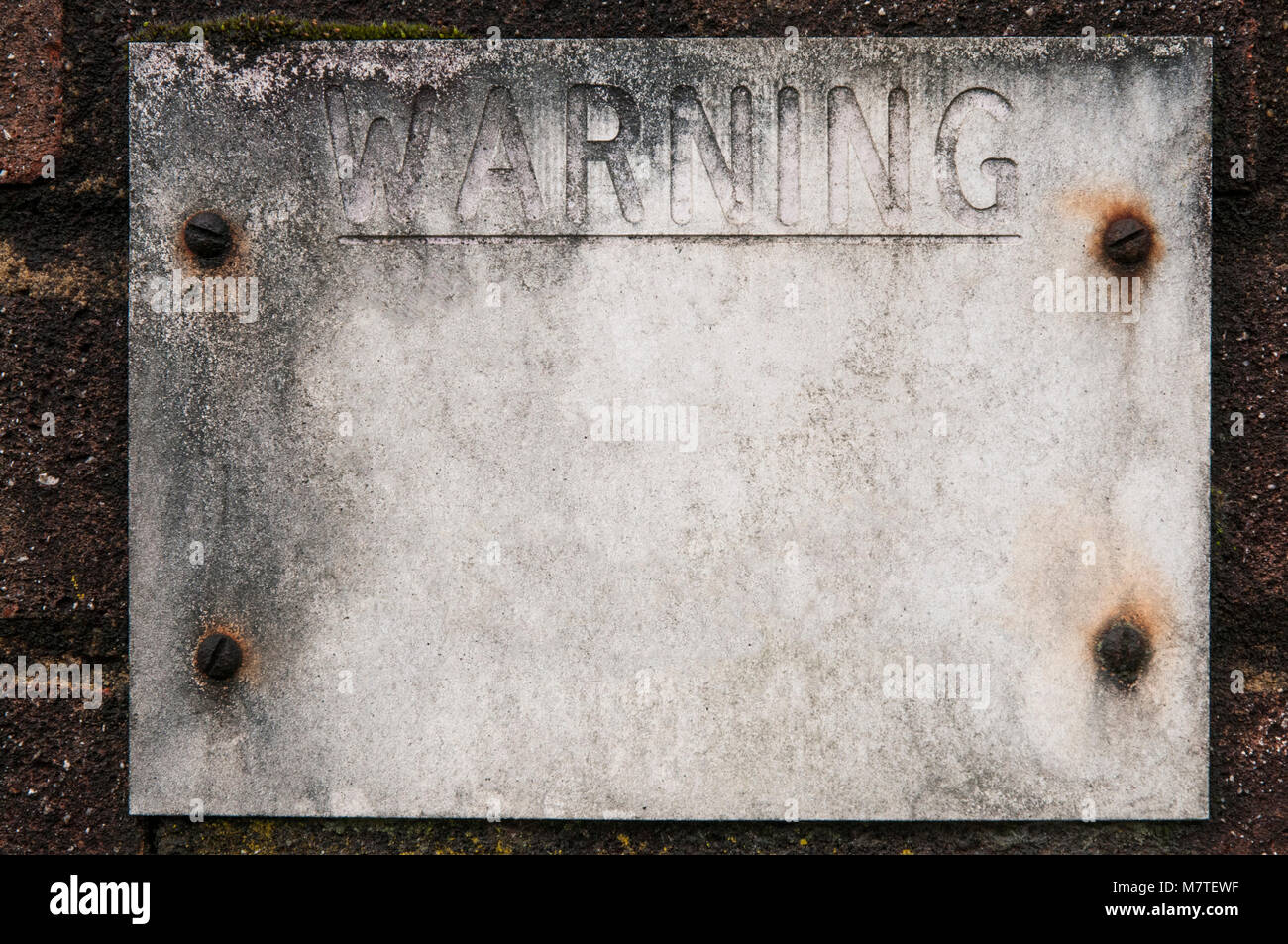 Weathered sign on brick wall saying WARNING. Retouched for additional ...