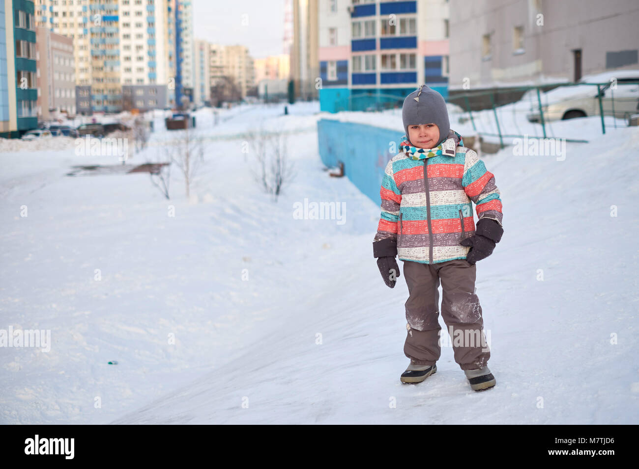 Funny little kid boy in colorful clothes playing outdoors in winter on ...