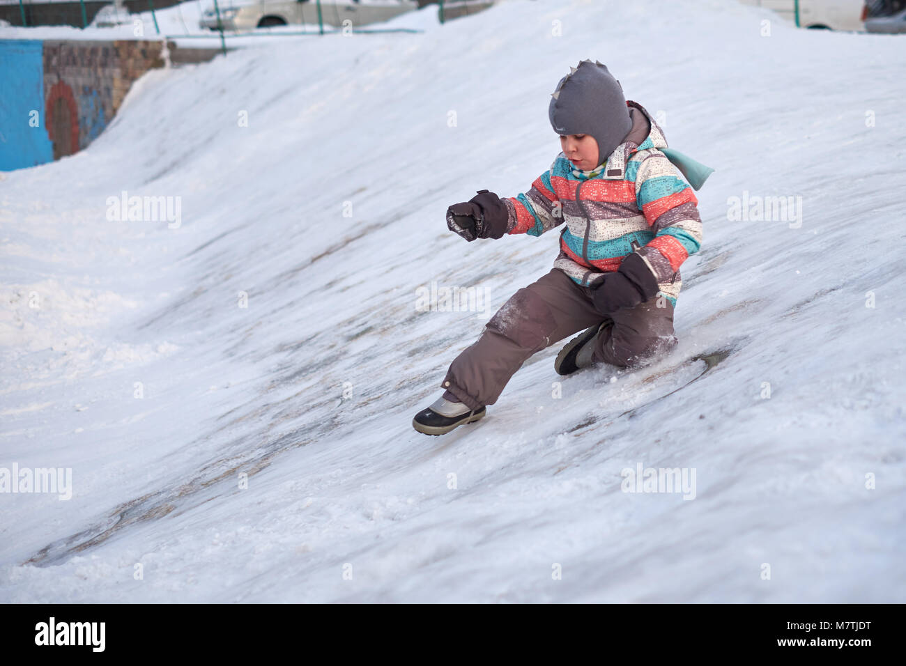 Funny little kid boy in colorful clothes playing outdoors in winter on ...