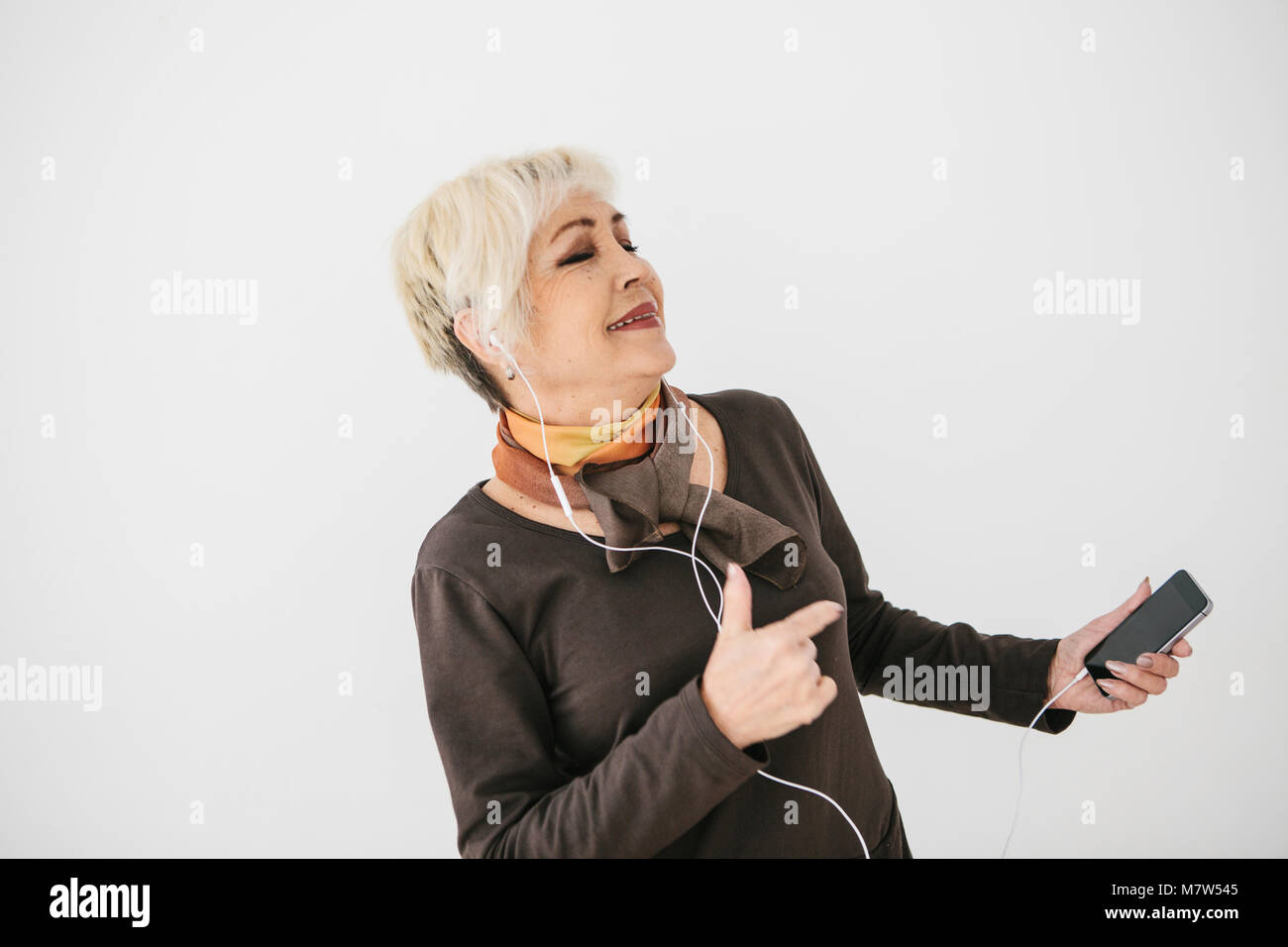 A positive elderly woman listens to music, dances and sings. The older ...