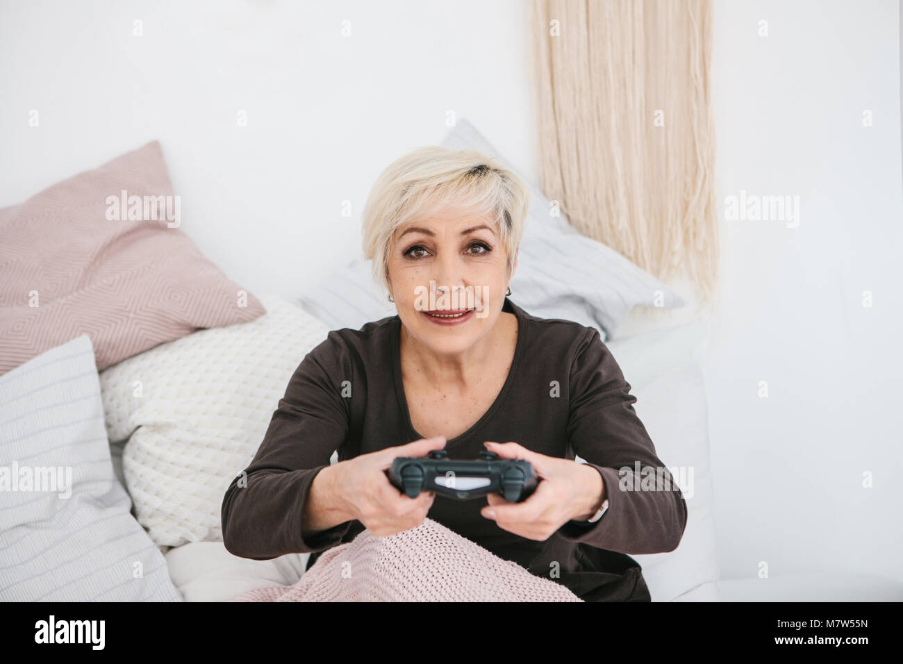 An elderly woman is playing a video game. Elderly person and modern ...