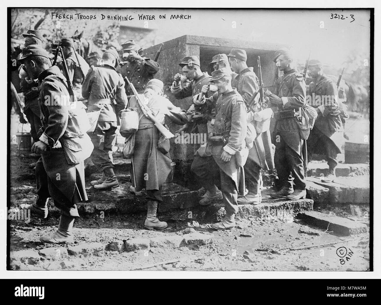 A photograph of French troops during a march, pausing to drink water ...