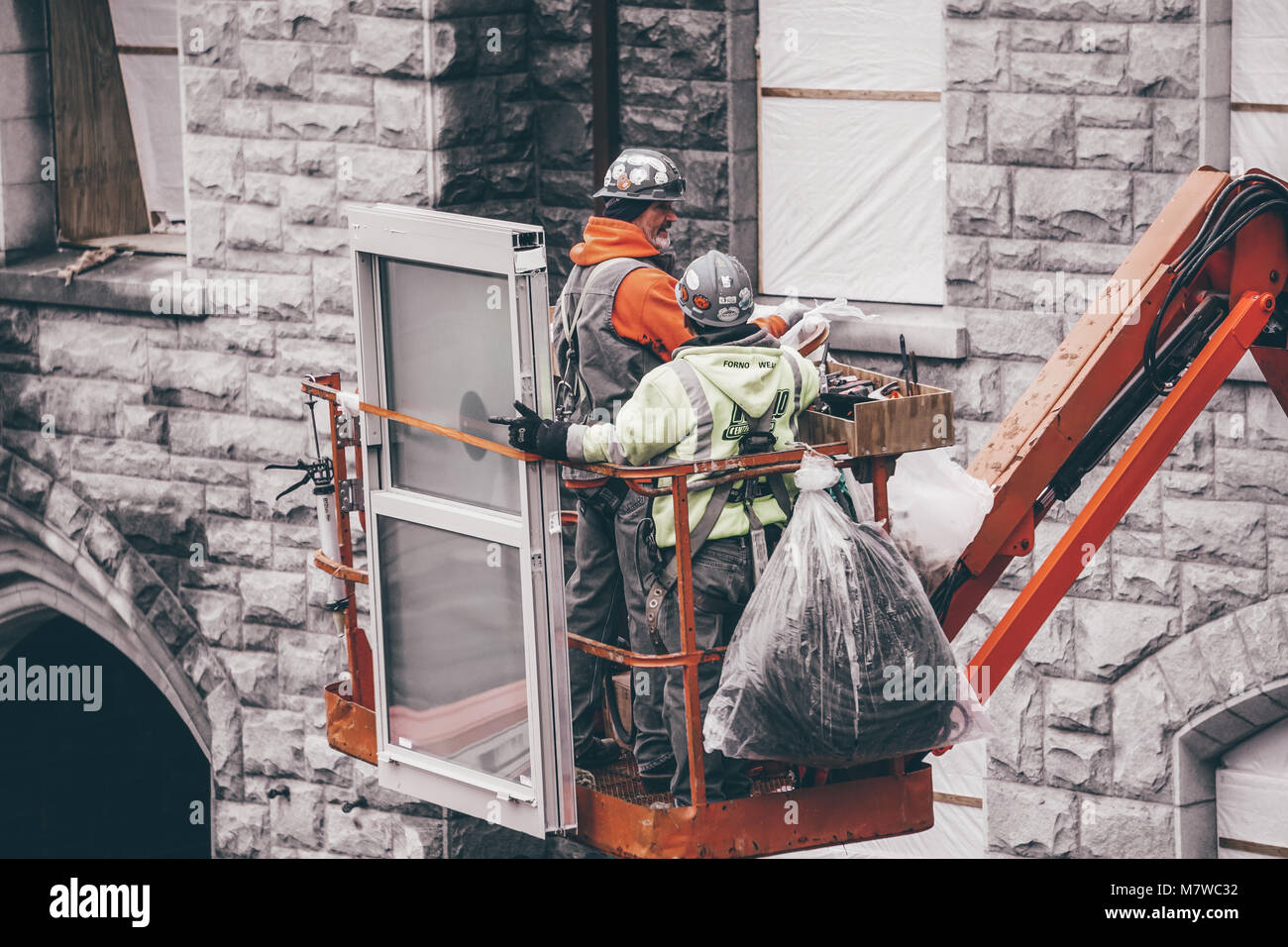 Workers operating lift to install windows Stock Photo - Alamy