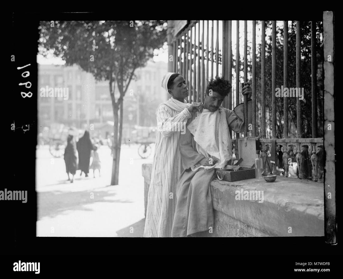 A photograph from Cairo, Egypt, depicting a street barber at work. The ...