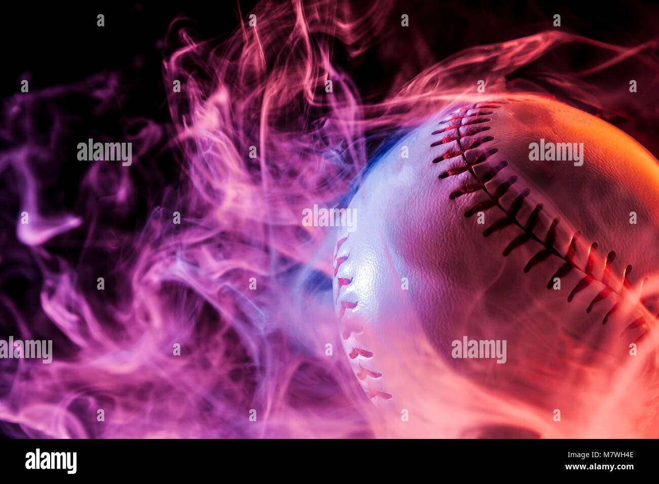 Close up of a white baseball ball in multi-colored red smoke from a ...