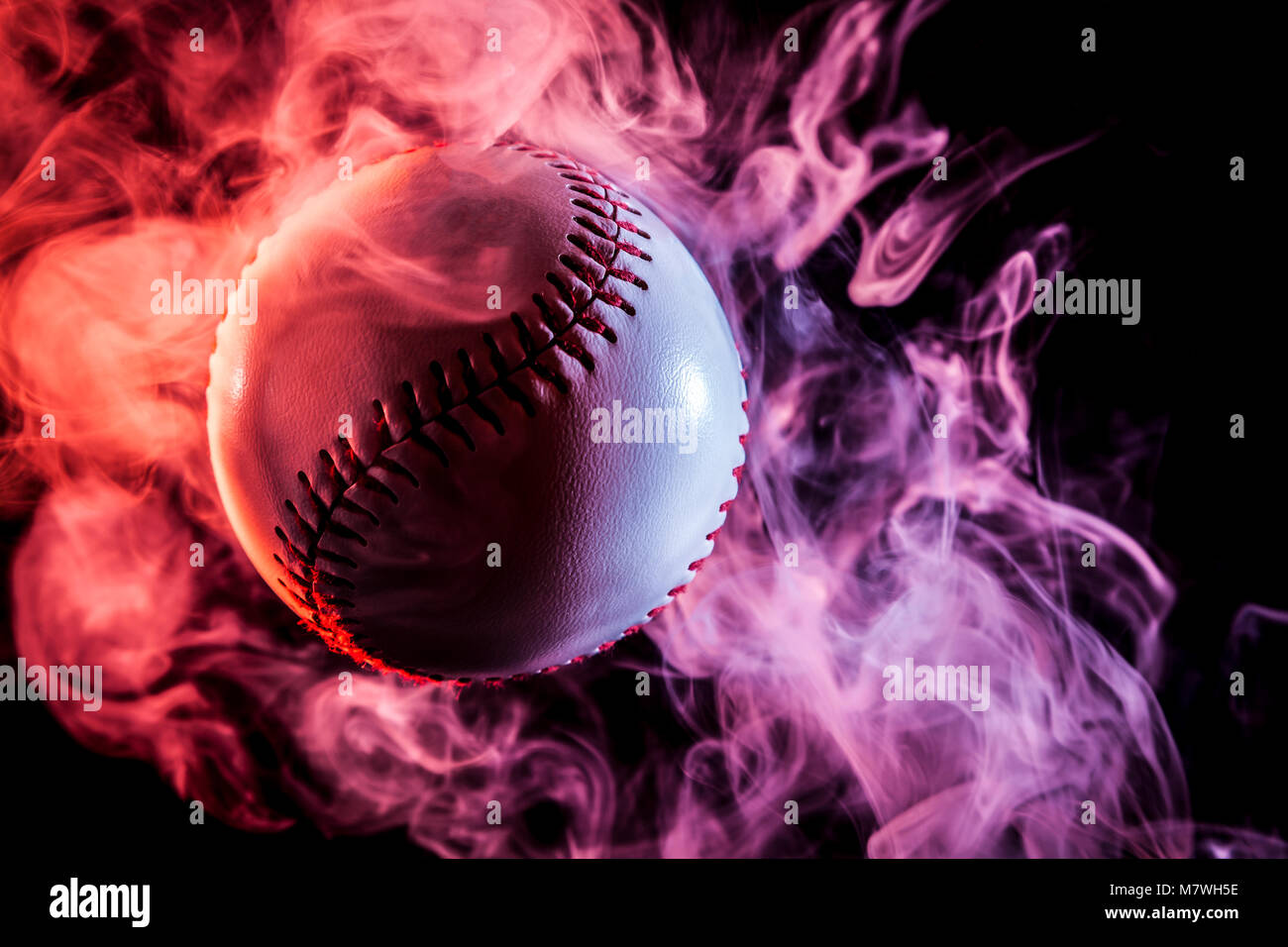 Colorful baseball ball in multi-colored red smoke from a vape on a ...