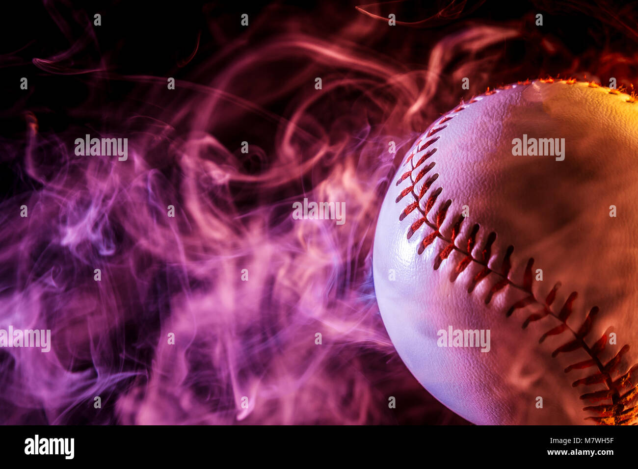 Colorful baseball ball in multi-colored red smoke from a vape on a ...