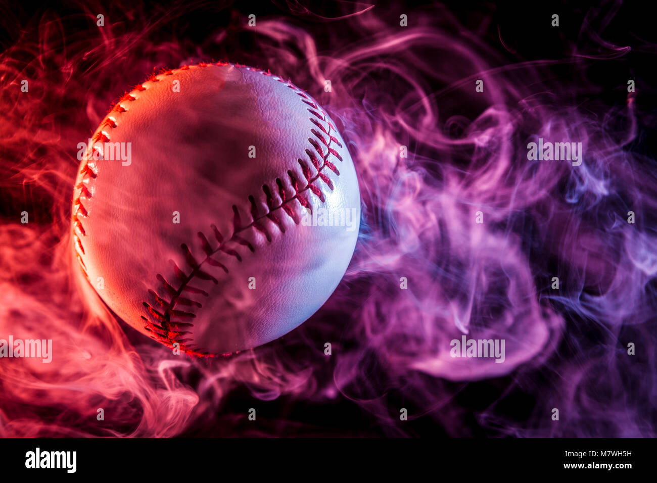 Colorful baseball ball in multi-colored red smoke from a vape on a ...