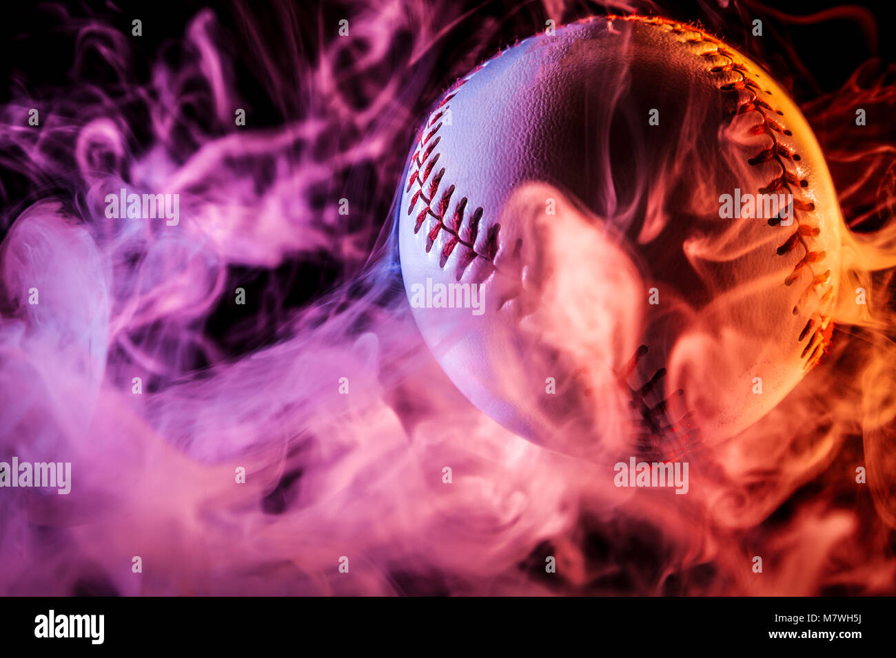 Close up of a white baseball ball in multi-colored red smoke from a ...