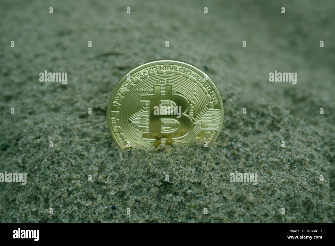 Golden bitcoin coin in the sand Stock Photo - Alamy