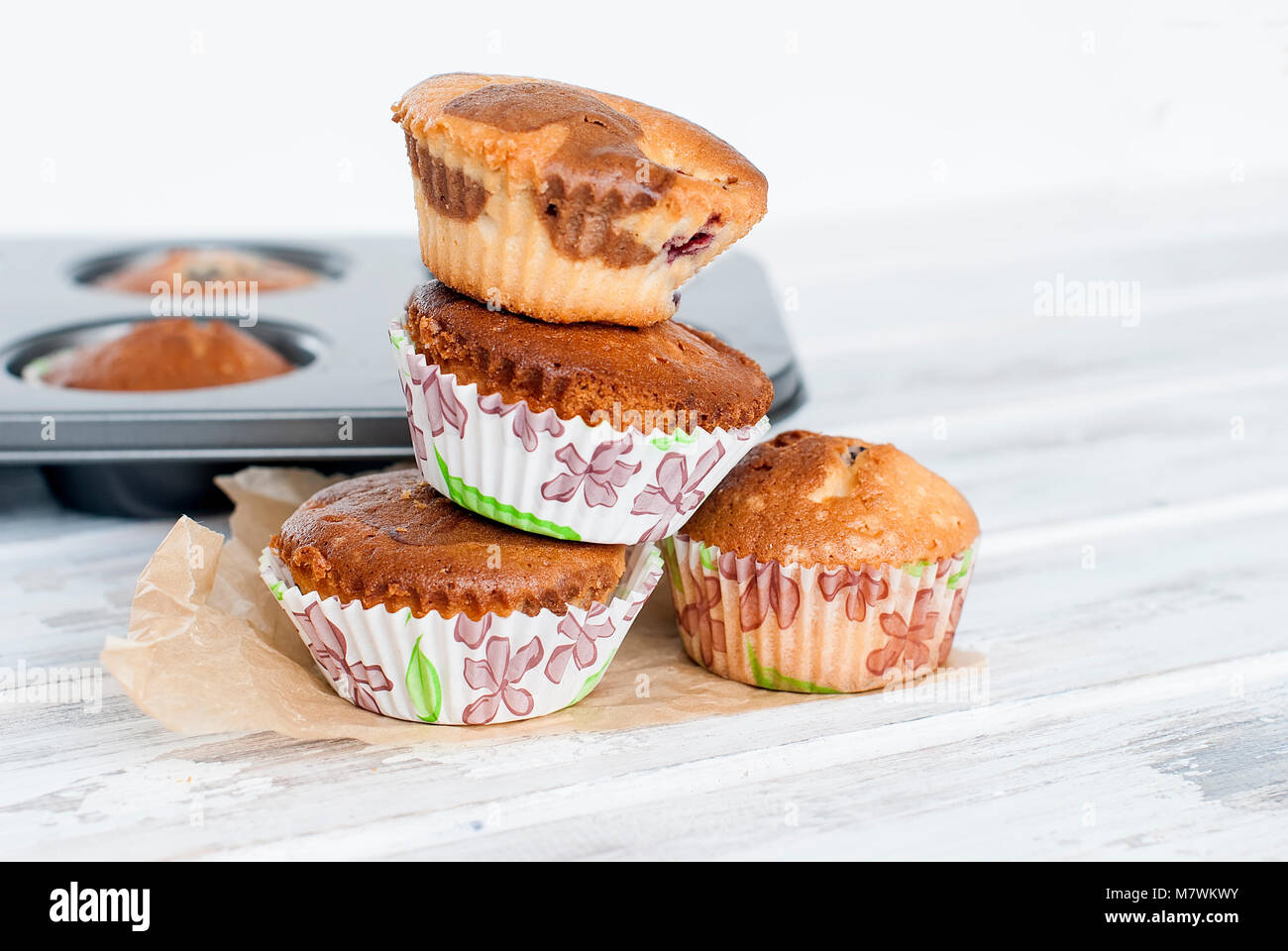 A row of chocolate and vanilla homemade muffins on a white wooden ...