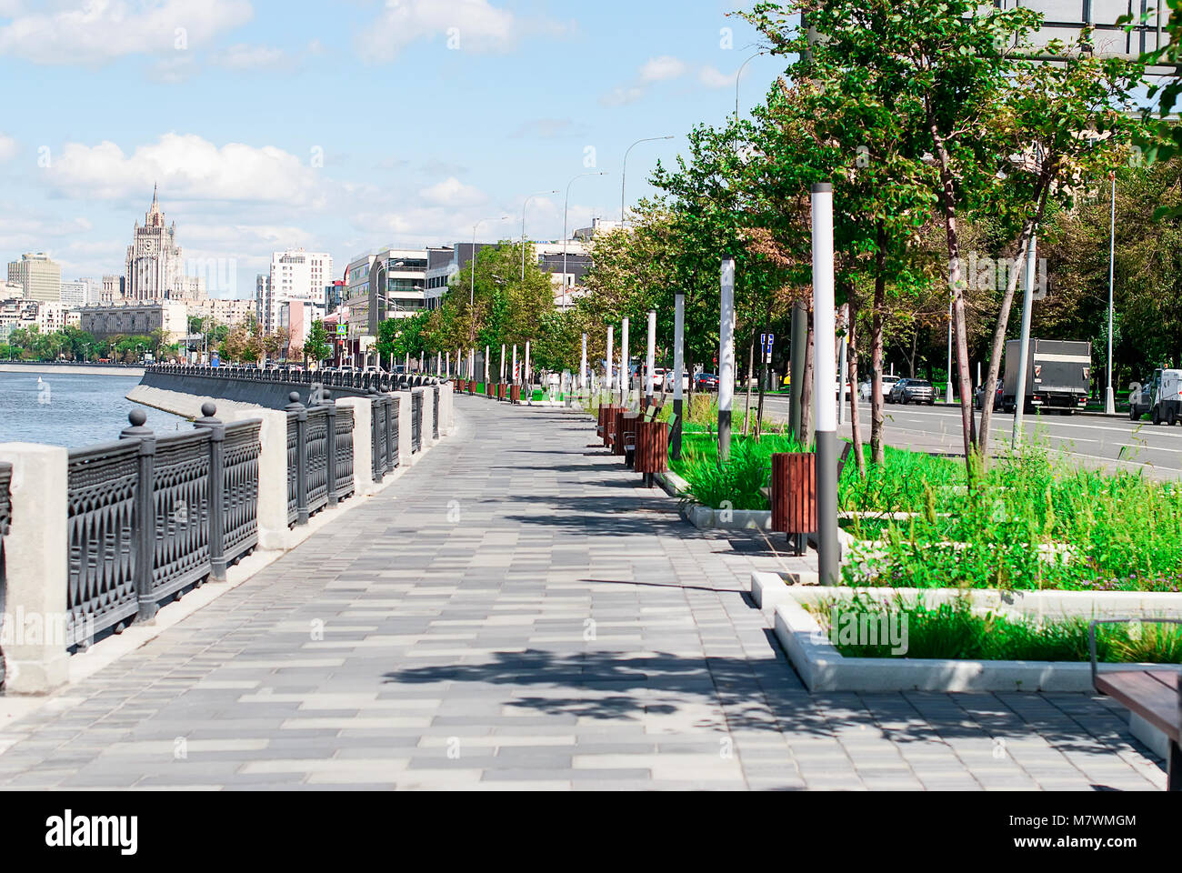Trees along waterfront promenade with lanterns by the business city ...