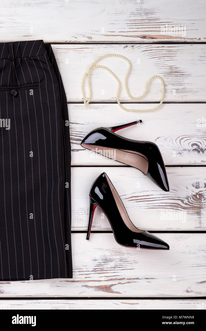 Cropped view flat lay woman clothes. Black high heel shoes, striped ...