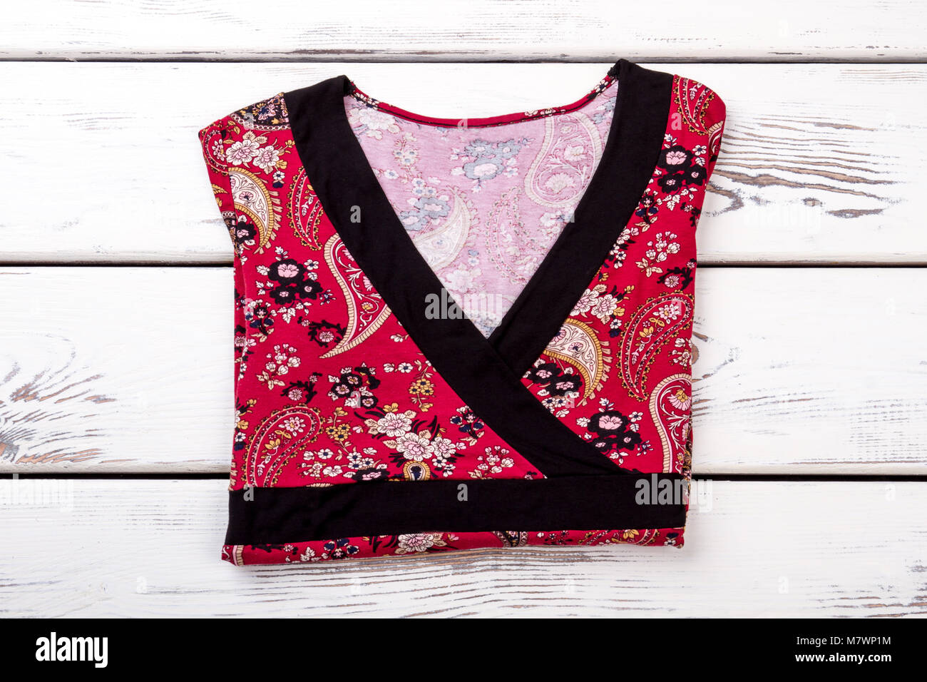 Folded pattern red blouse. Flat lay top view. White wooden background ...