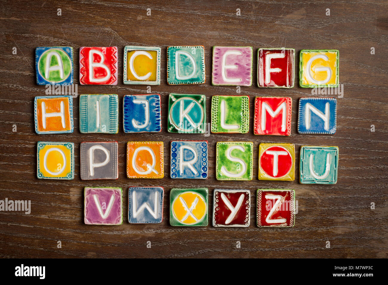 Colorful handmade ceramic alphabet on wood texture Stock Photo - Alamy